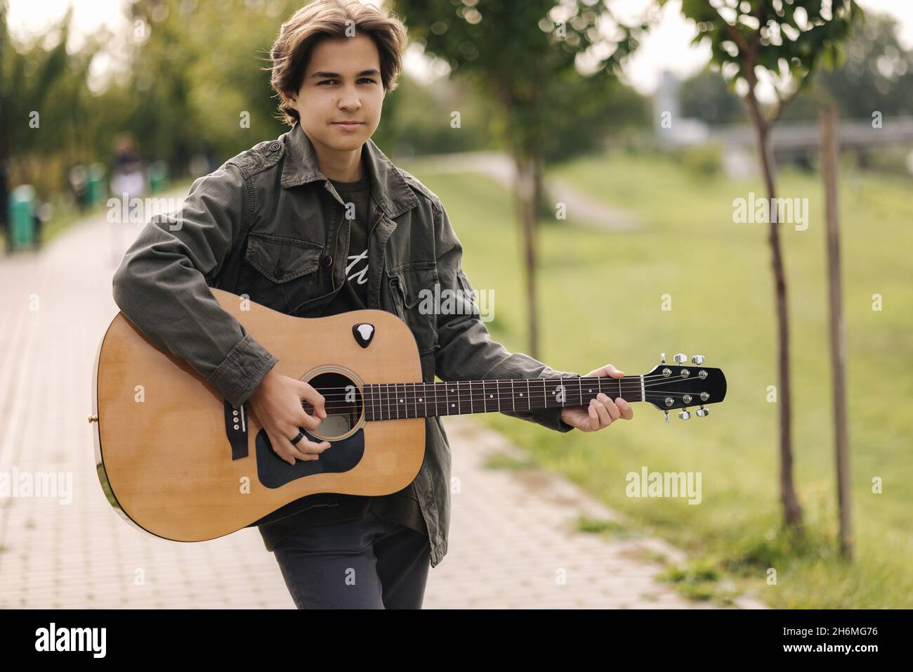 Concentrated teenage boy musician playing acoustic guitar outdoor ...