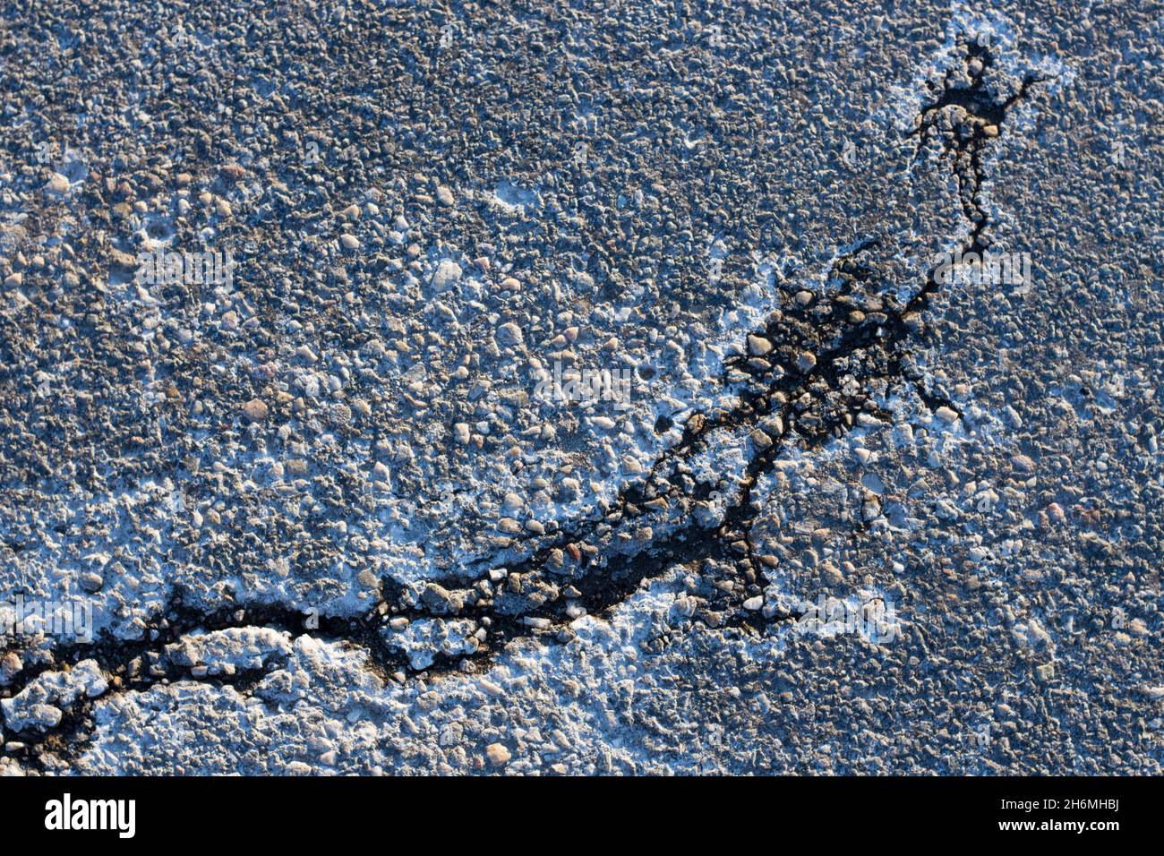 Crack in asphalt during winter with remains of road salt Stock Photo ...