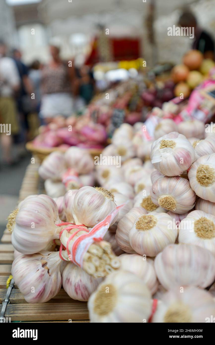 Vertical shot of ripe garlic bulbs on a stall in a French market with a ...