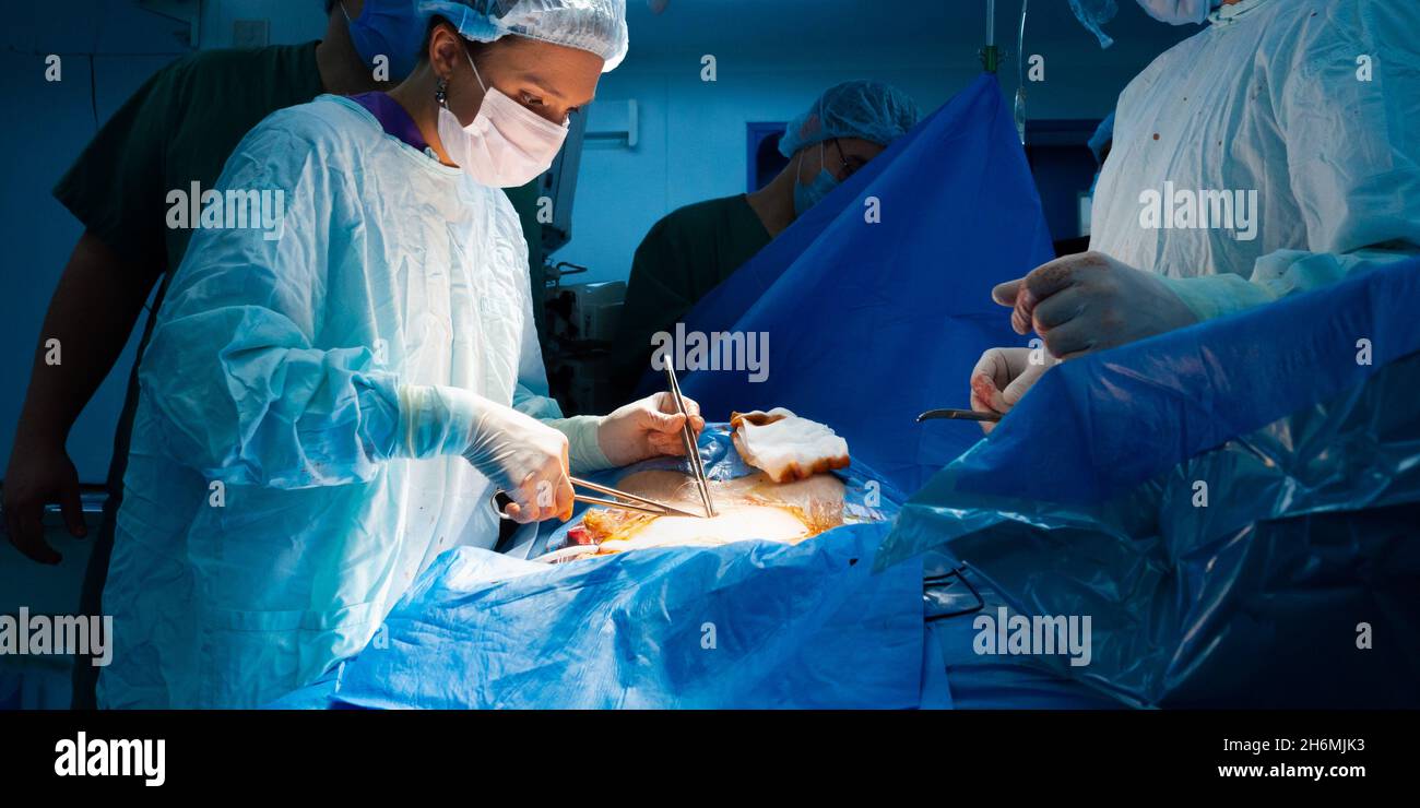 A female surgeon sutures the patient's skin at the end of the operation ...