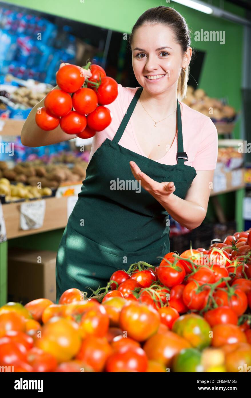 Saleswoman offering tomatoes in supermarket Stock Photo - Alamy