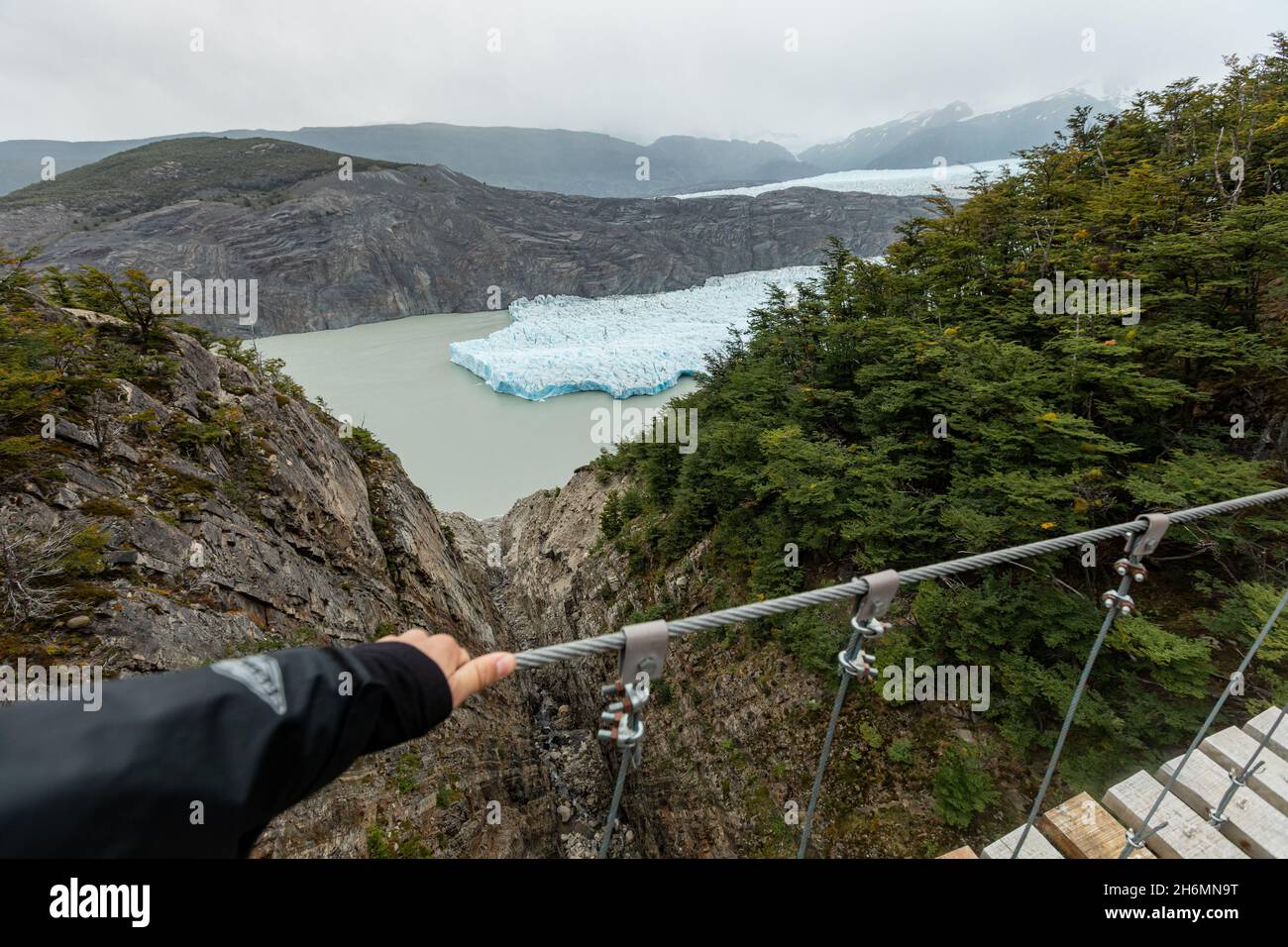 A woman's hands holds a wire rope of the pedestrian suspension bridge ...