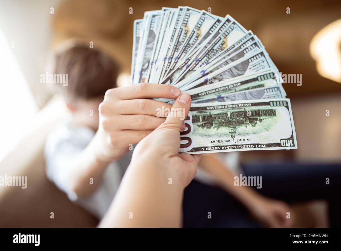 mother gives her son a bundle of dollars. The client pays for the work ...