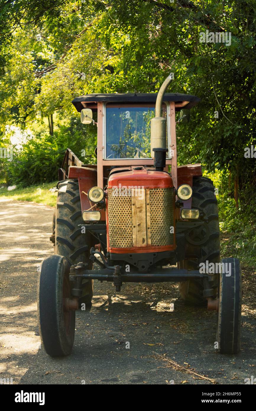 Old tractor by green trees in a rural area Stock Photo - Alamy