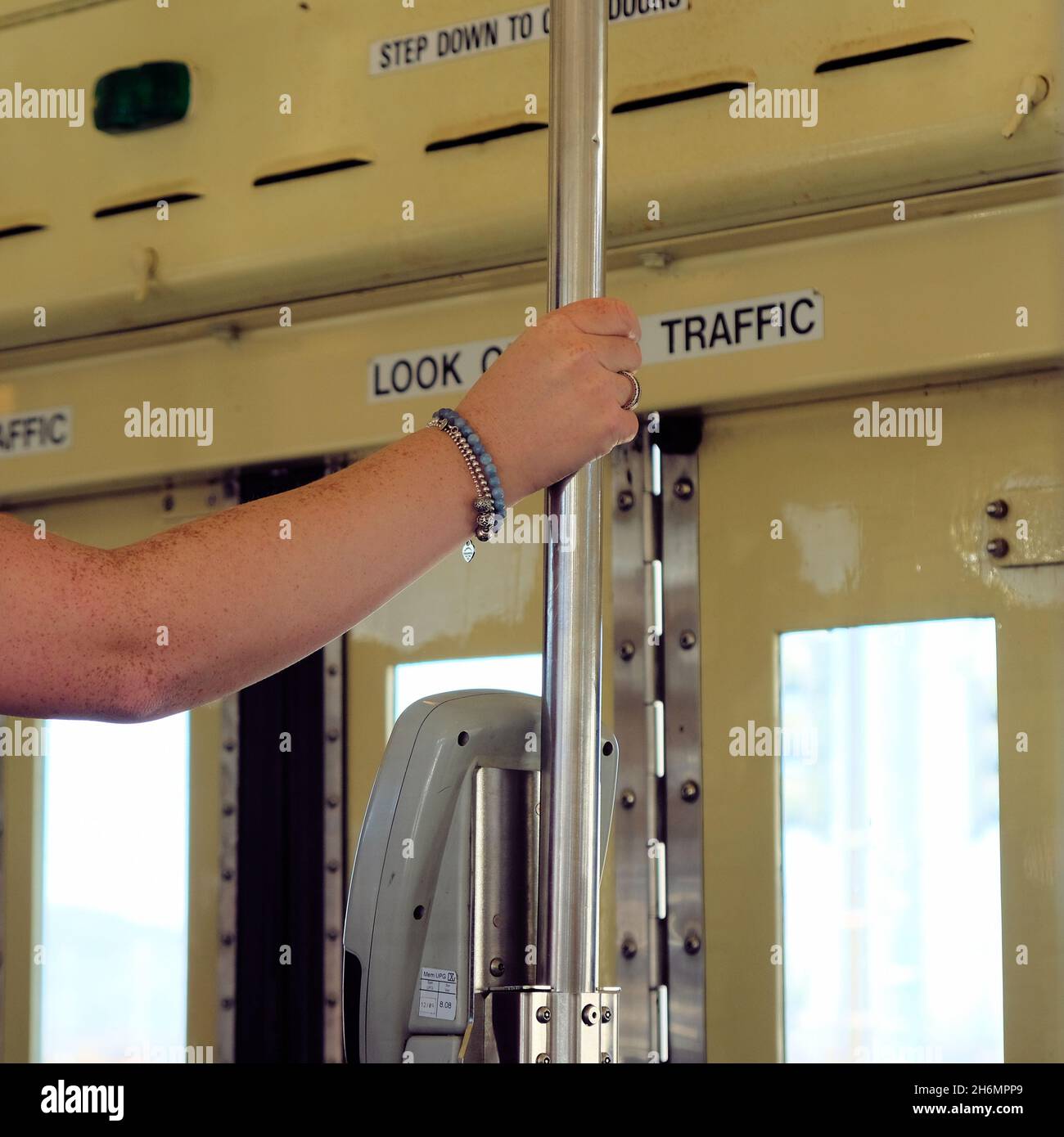 A young persons' arm and hand holding on to a bus stanchion for safety ...
