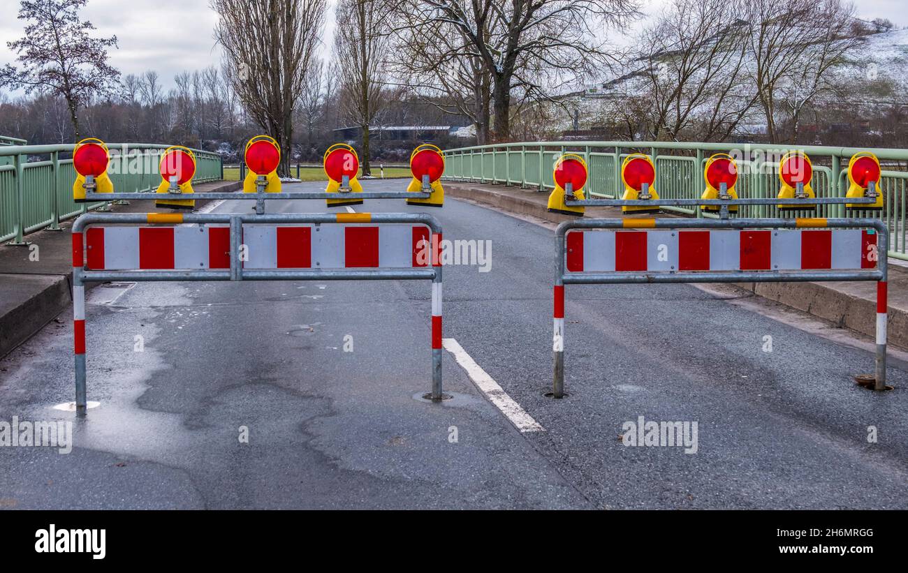 "Road closed" barriers with signal lights placed on the wet ground ...
