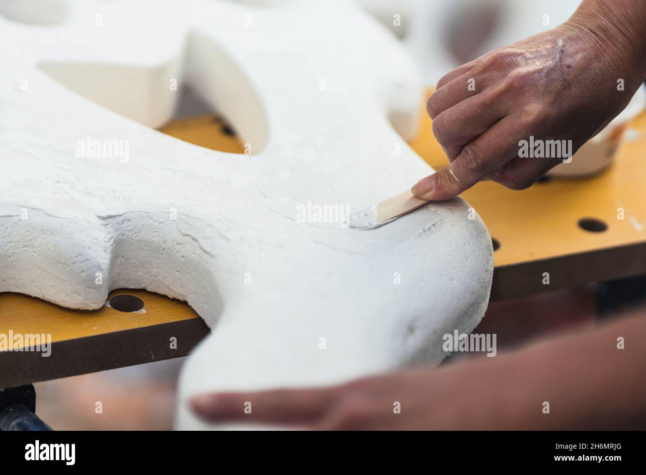Person spreading cream to smooth a polystyrene figure using a spatula ...