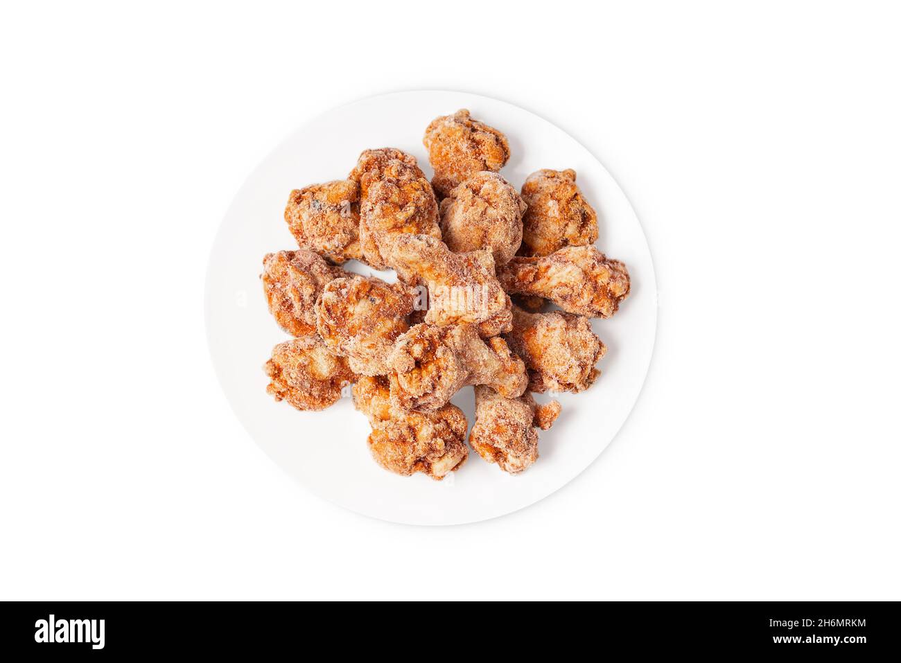Frozen semi-cooked chicken wings on a white plate on a white background ...