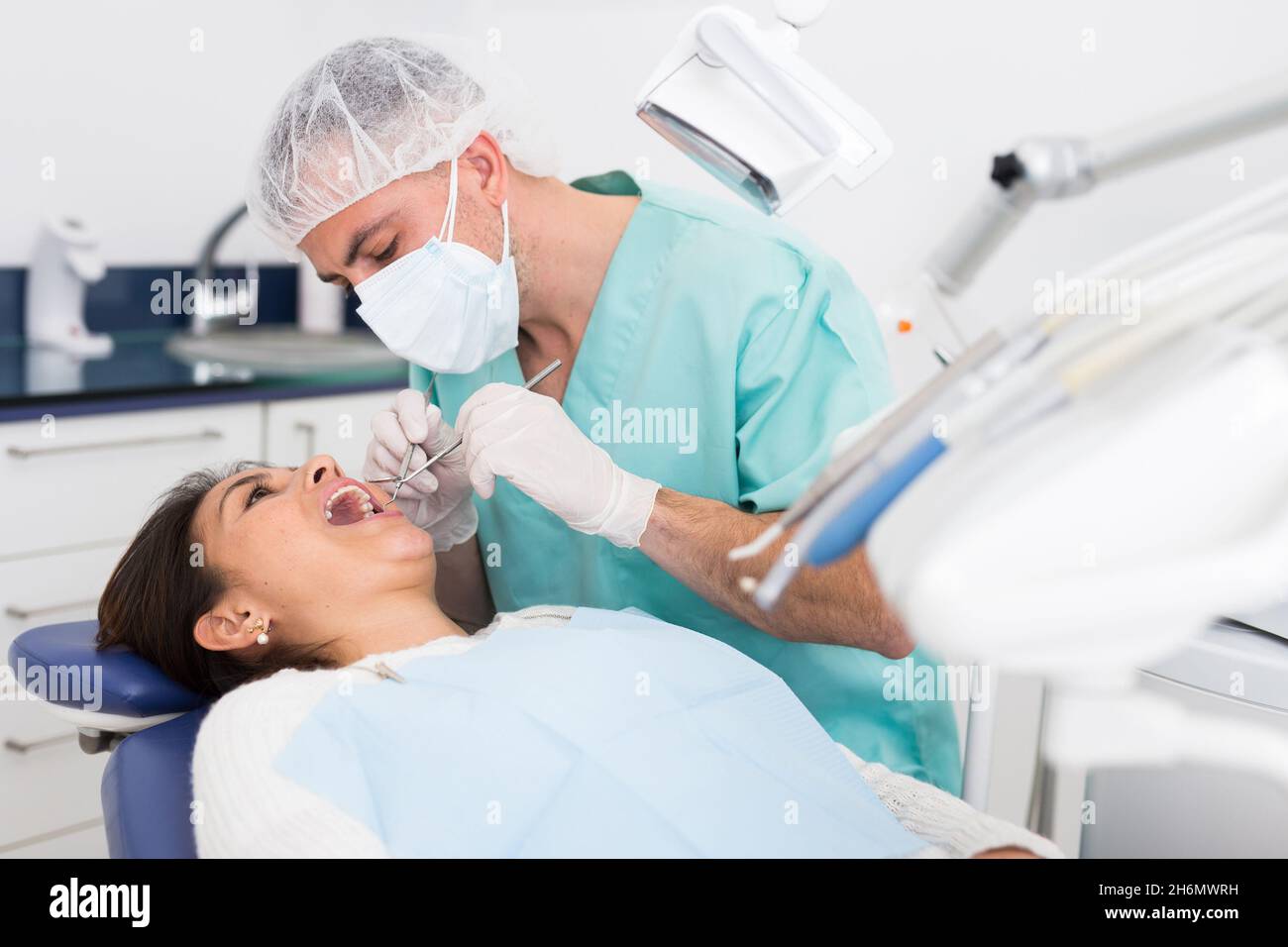 Dentist man examining a latin female patient teeth Stock Photo - Alamy