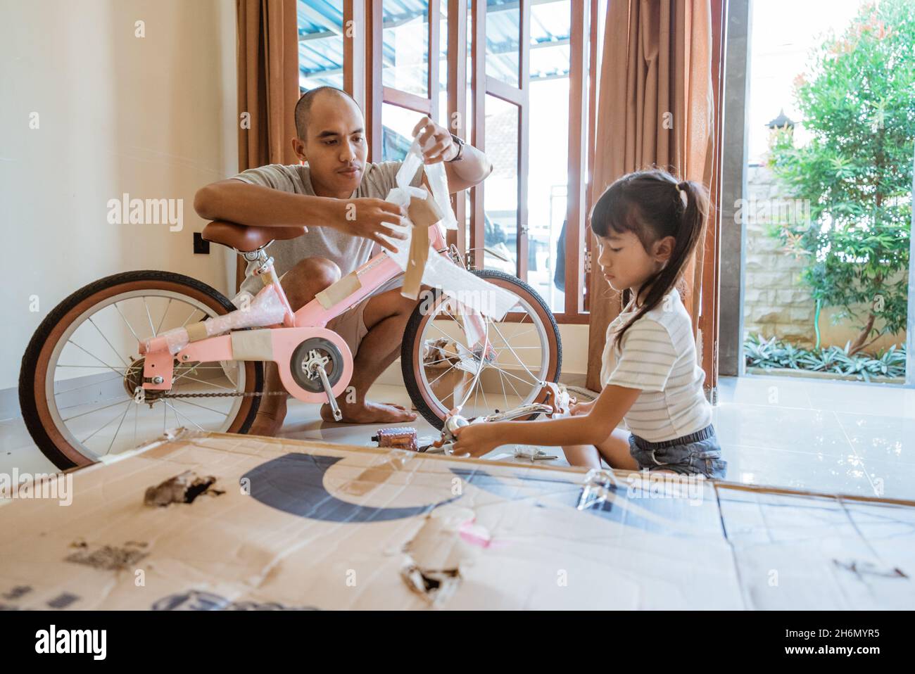 Little asian daughter and father holding new unassembled mini bike ...