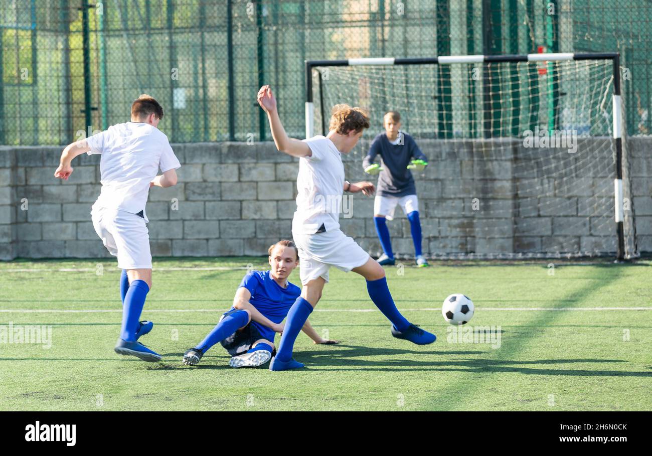 Game of football match between two teams of teenagers in white and blue ...