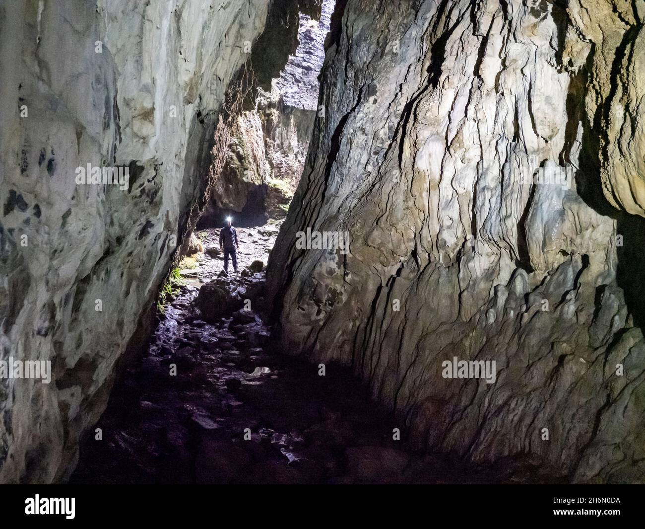 A caver in the entrance of the Spar Cave near Elgol, Isle of Skye ...