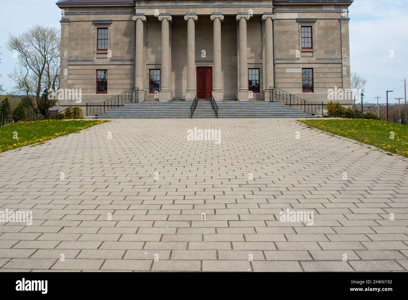 A wide brick entrance to a large government building. There's a red ...