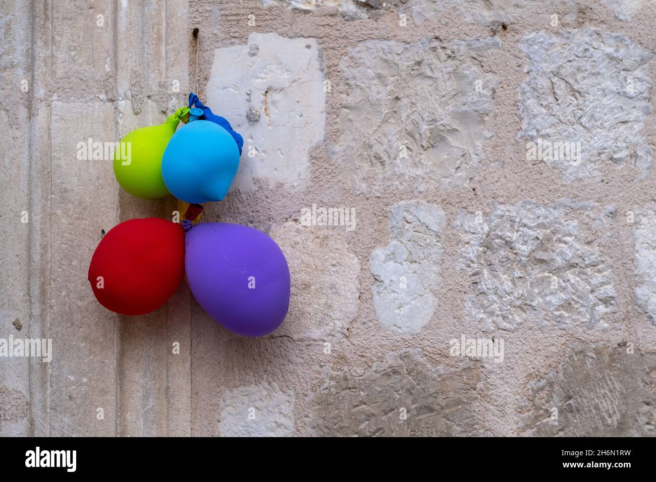 Set of deflated colorful balloons hanging from a wall Stock Photo - Alamy