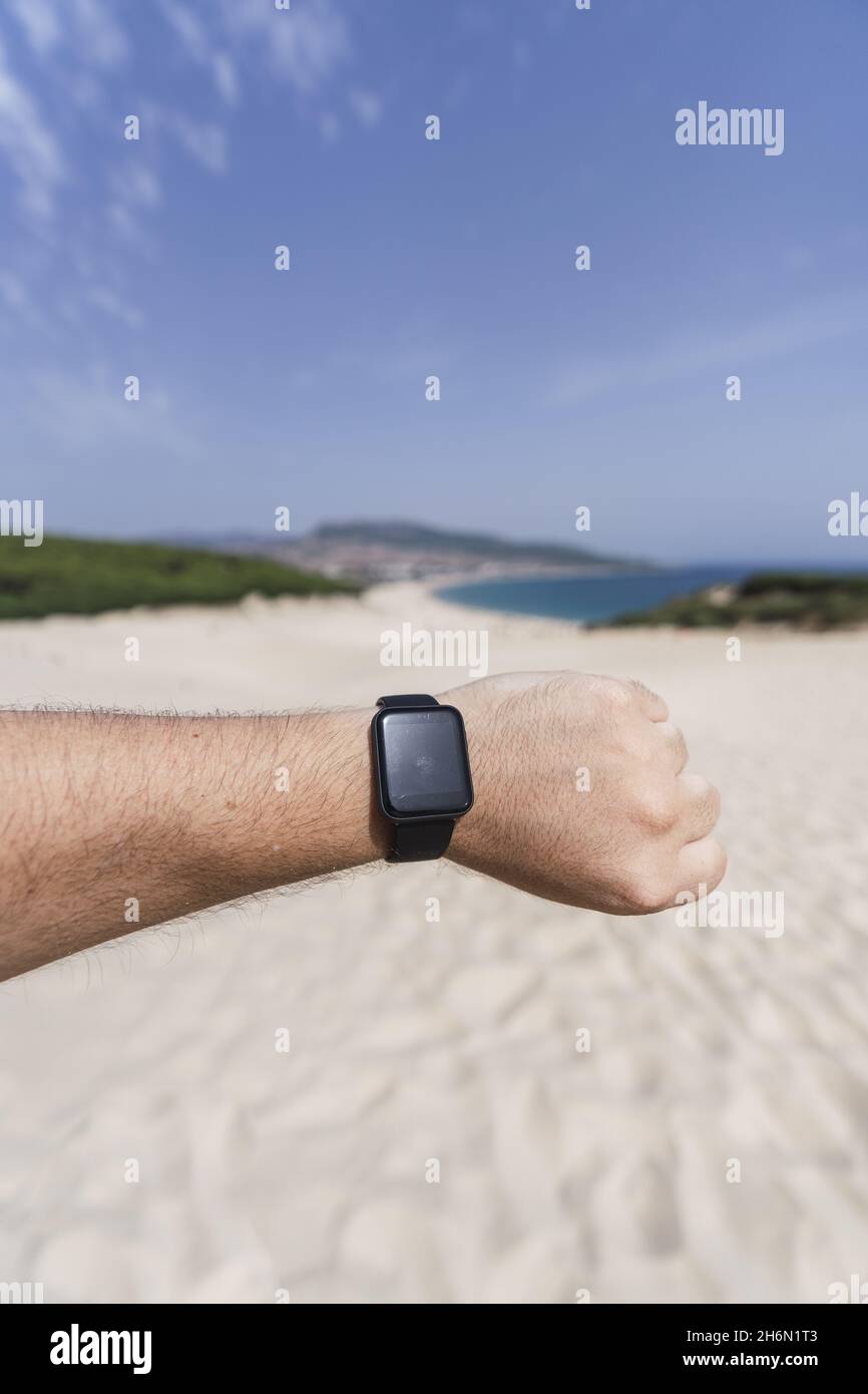 Vertical shot of a hand with a smartwatch on a beach Stock Photo - Alamy