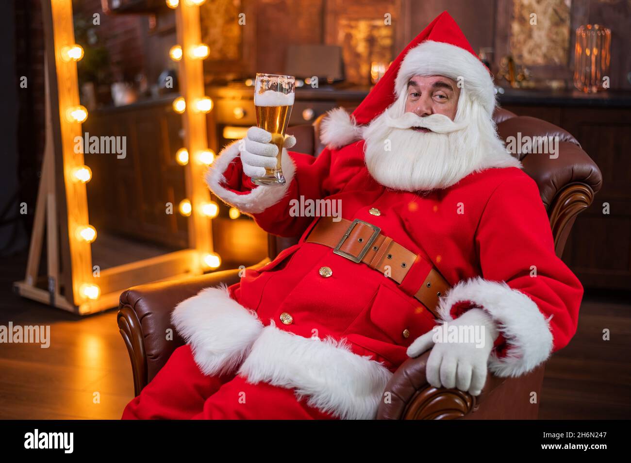Santa Claus drinks beer while sitting in a leather armchair Stock Photo ...