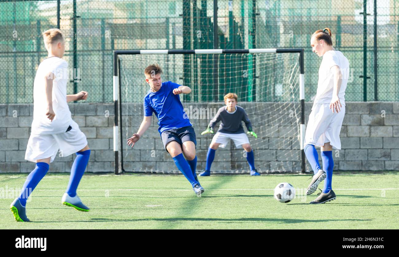 Game of football match between two teams of teenagers in white and blue ...