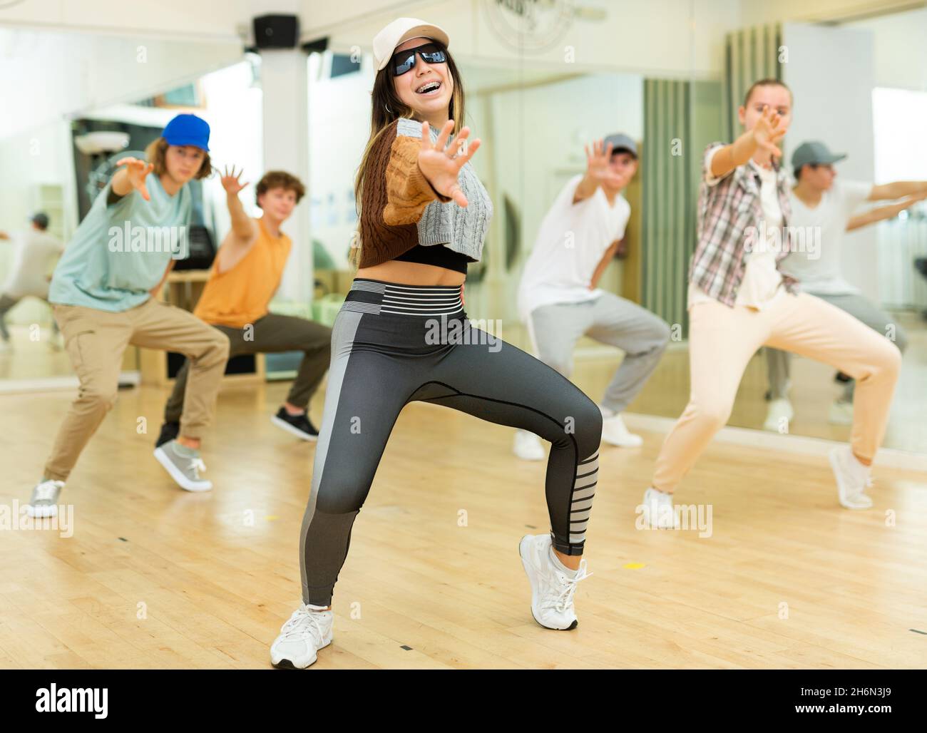 Cheerful hispanic teenage girl practicing hip-hop movements in studio ...