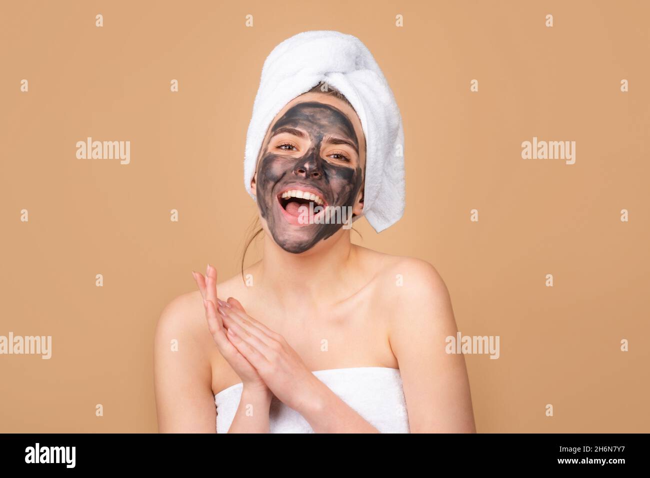 Mud facial mask, face clay mask spa. Beautiful laughing woman with ...