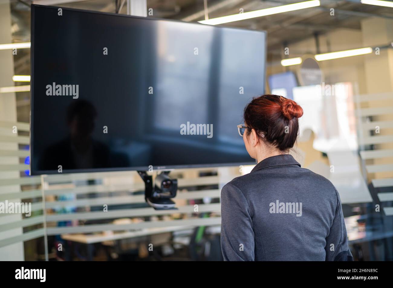 Business woman looking at the TV screen in the office Stock Photo - Alamy
