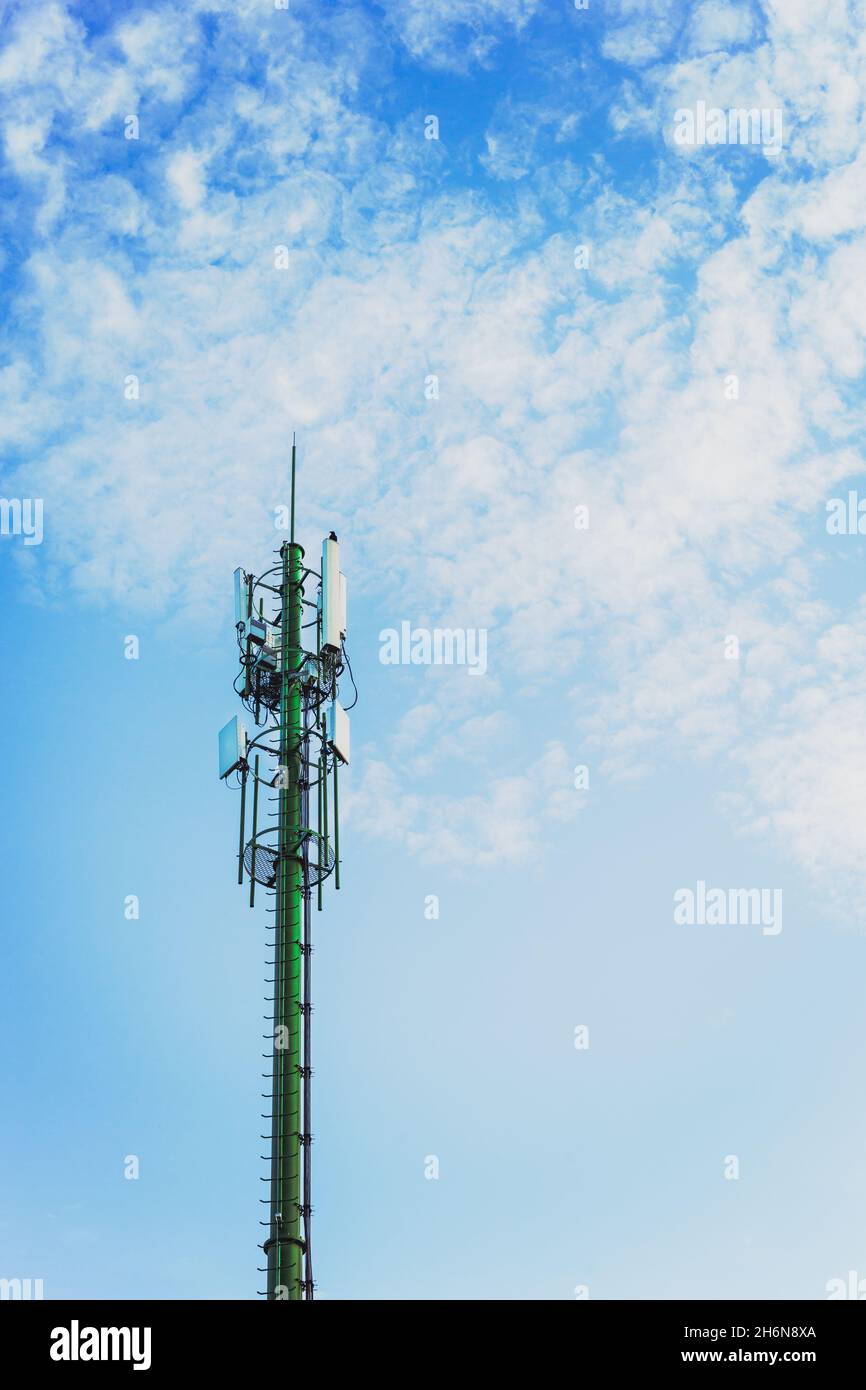 Vertical of telecommunication tower with blue sky and white clouds ...