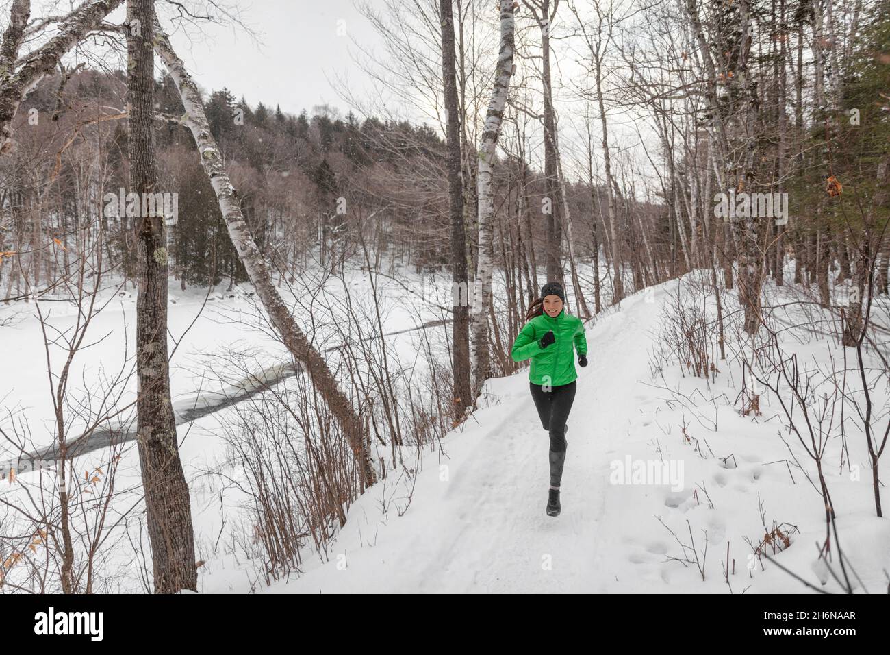 Winter snow runner woman running outside on cold winter day in forest ...