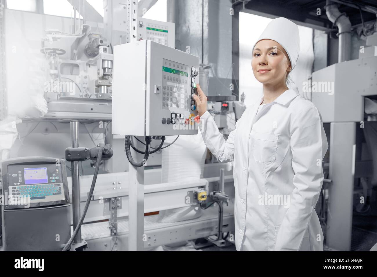 Factory engineer woman operating machine control panel in mill flour ...