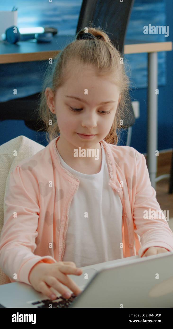 Young child using keyboard on laptop for homework and online courses for distance education ...