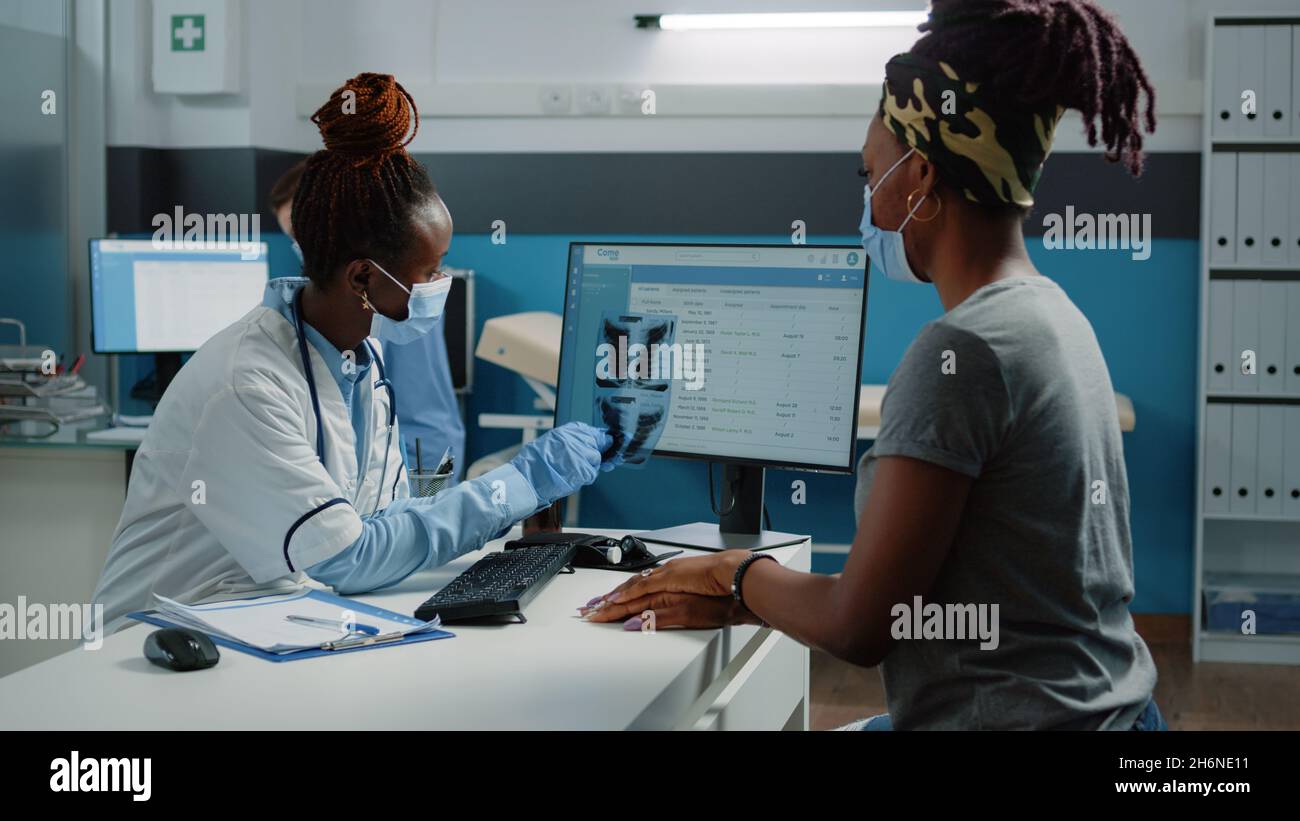 Doctor and patient with face masks analyzing x ray scan for medical ...