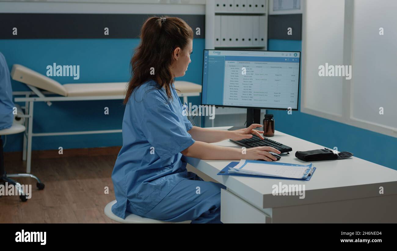Woman working as nurse with computer and documents in cabinet, checking ...