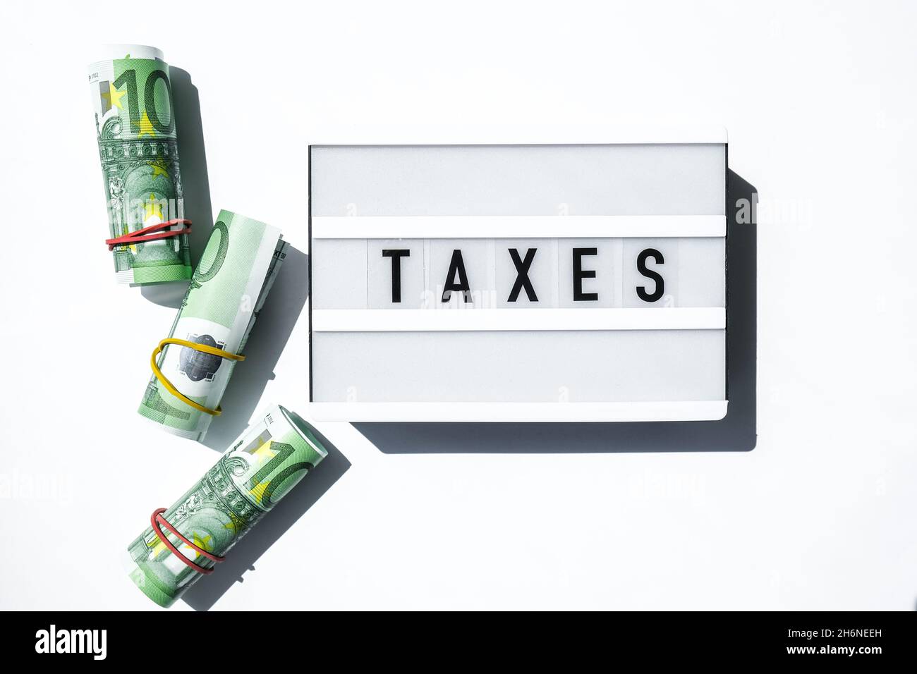 Lightbox board with word TAXES in black letters around Euro banknotes ...