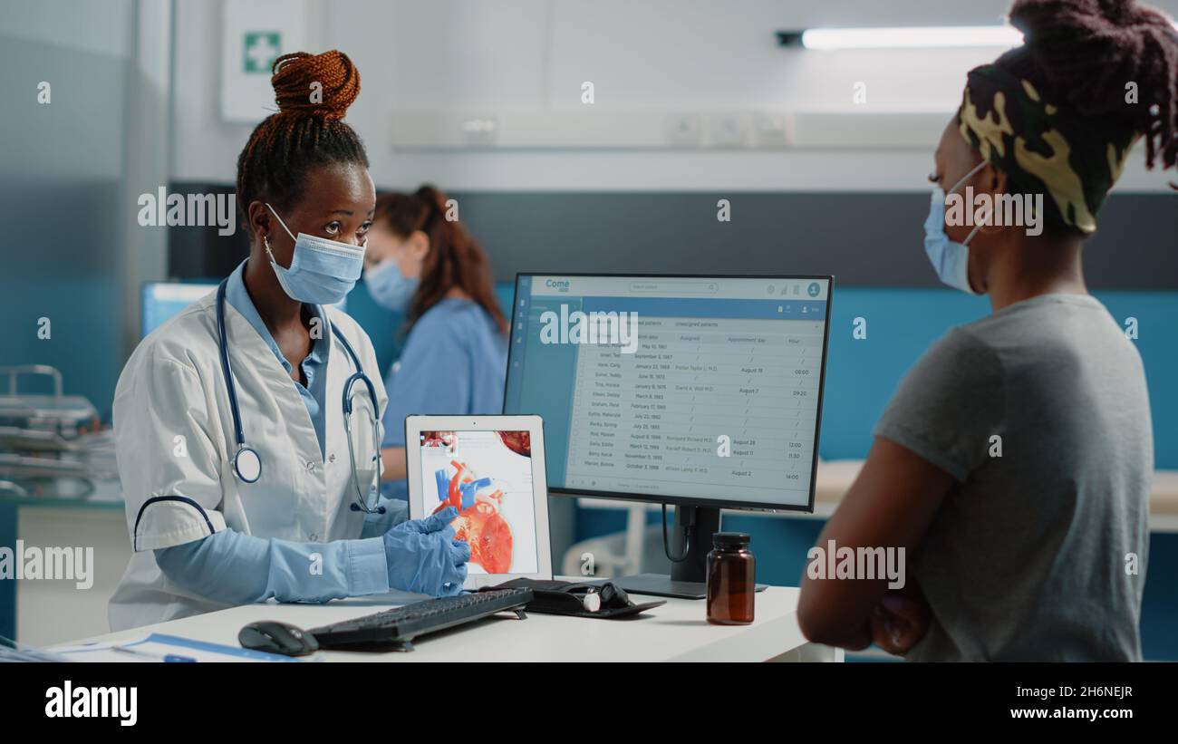 Doctor pointing at tablet with heart organ on screen, explaining ...
