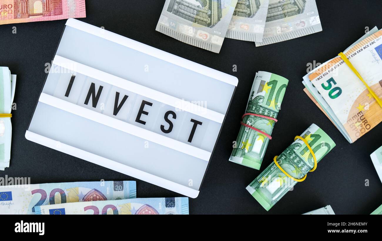 Lightbox board with word INVEST in black letters around euro banknotes ...