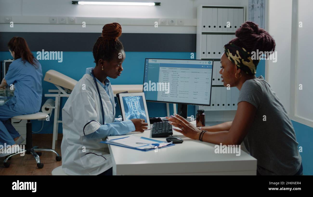 African american patient and doctor looking at radiography on tablet ...