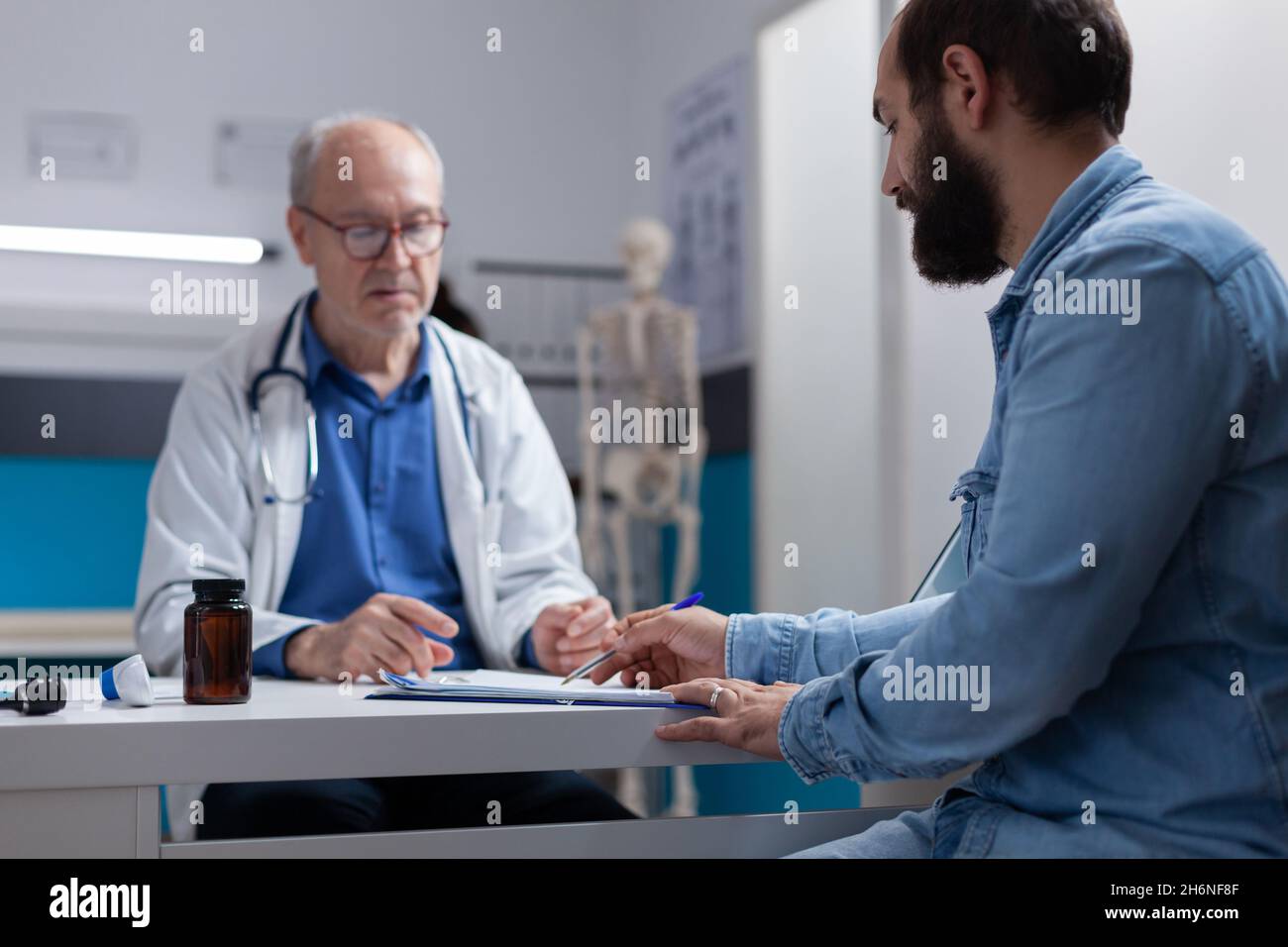 Patient signing checkup papers for prescription at medical appointment ...