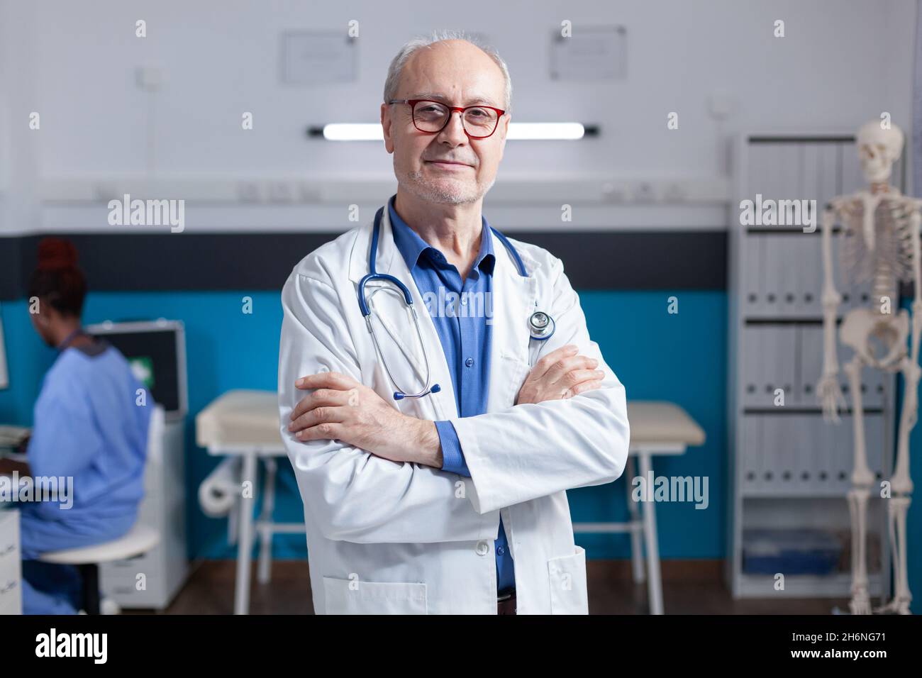 Portrait of smiling medic with white coat and stethoscope standing with ...