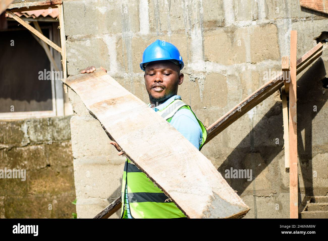 African male construction worker with a helmet working with a plank on ...