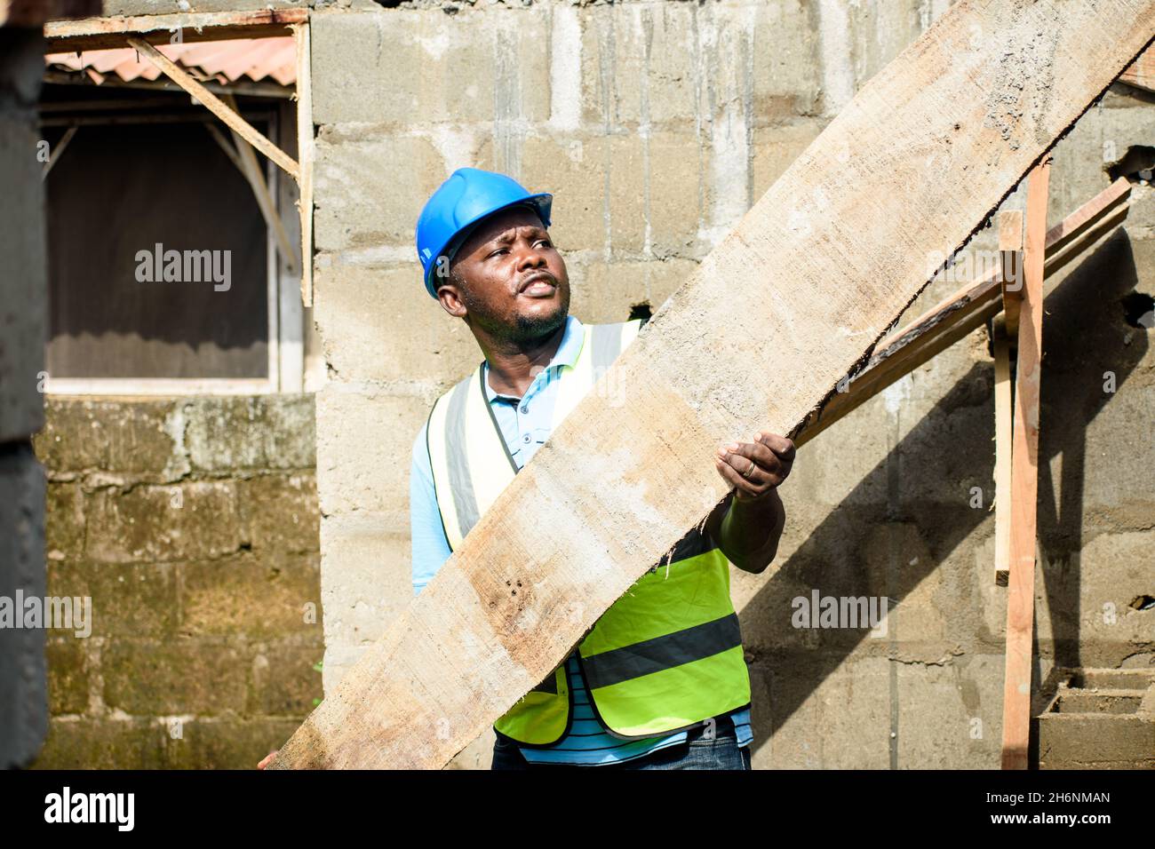 African male construction worker with a helmet working with a plank on ...