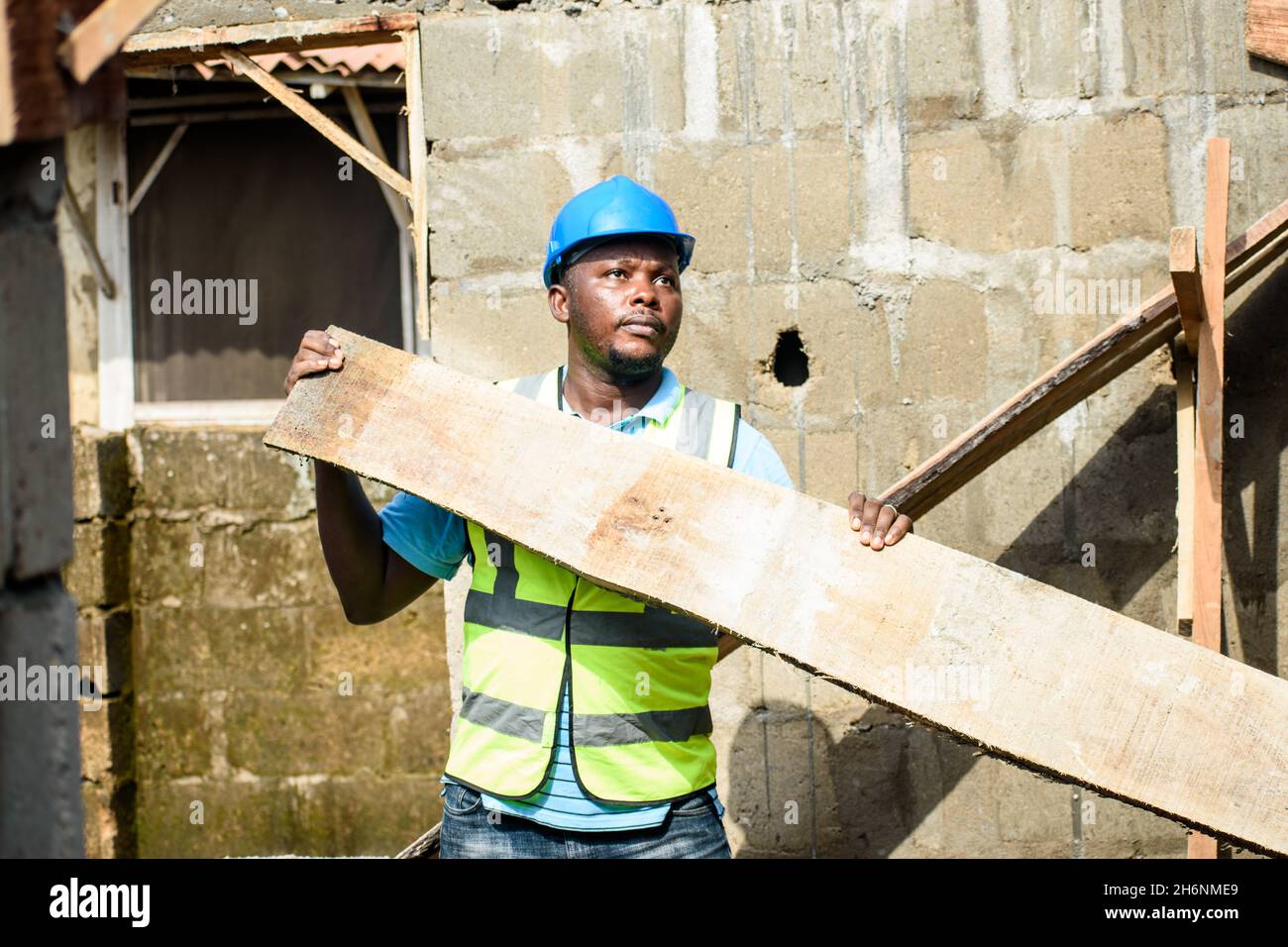 African male construction worker with a helmet working with a plank on ...