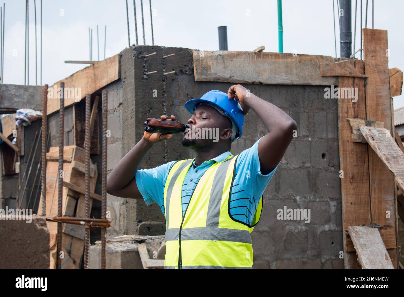 View of a builder with a blue helmet drinking from a bottle on a ...