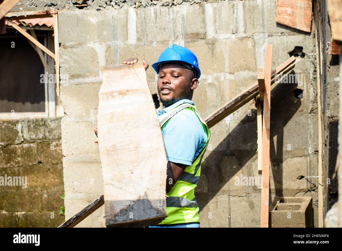 African male construction worker with a helmet working with a plank on ...