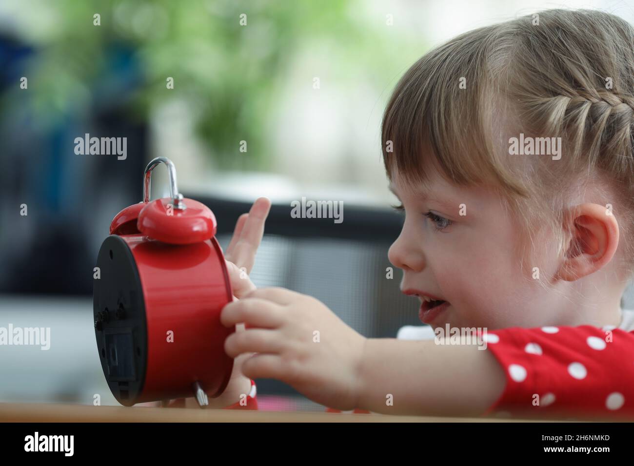 Curious little pretty girl explore red clock touch dial with finger ...