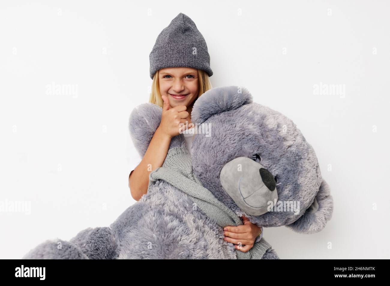 Positive little girl teddy bear in the hands of fun on a light ...