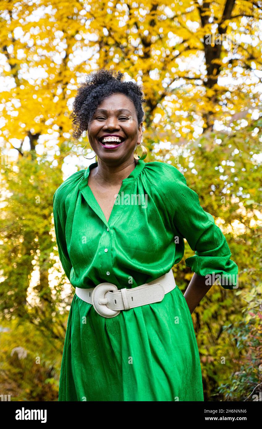Portrait of a laughing, dark-skinned woman with curls and green dress ...