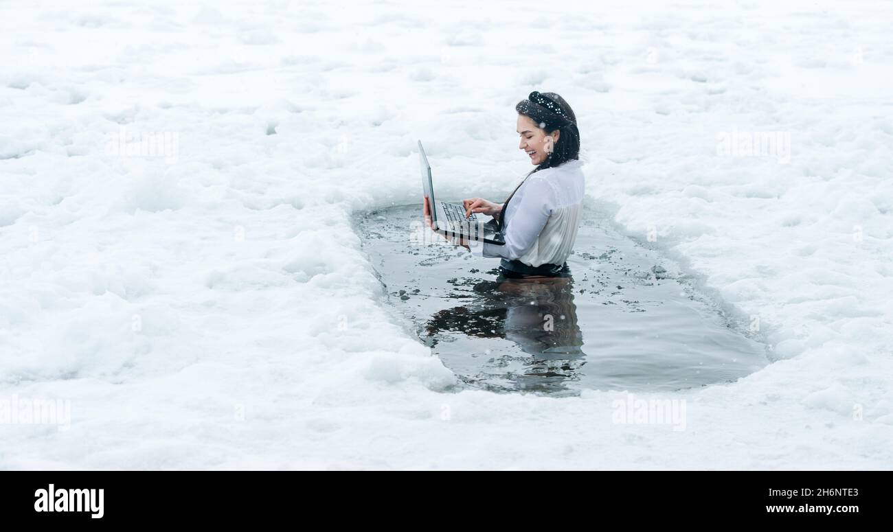 Girl with laptop in frozen lake ice hole. Woman hardening the body in ...