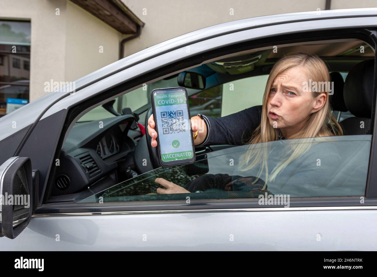 driver in car shows a digital covid-19 immunity vaccine passport, new ...