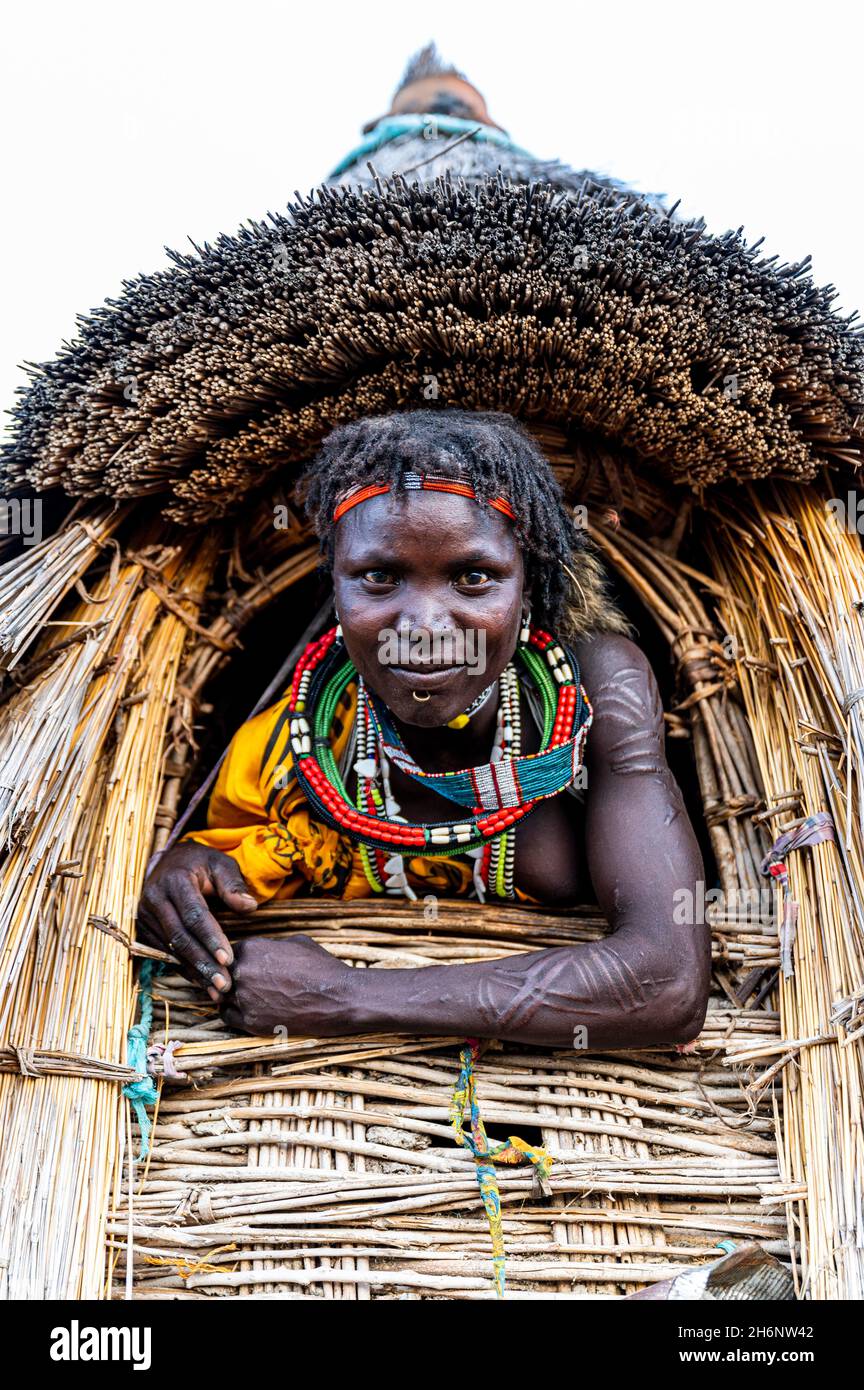 Traditional dressed girl from the Toposa tribe sitting in a grain ...