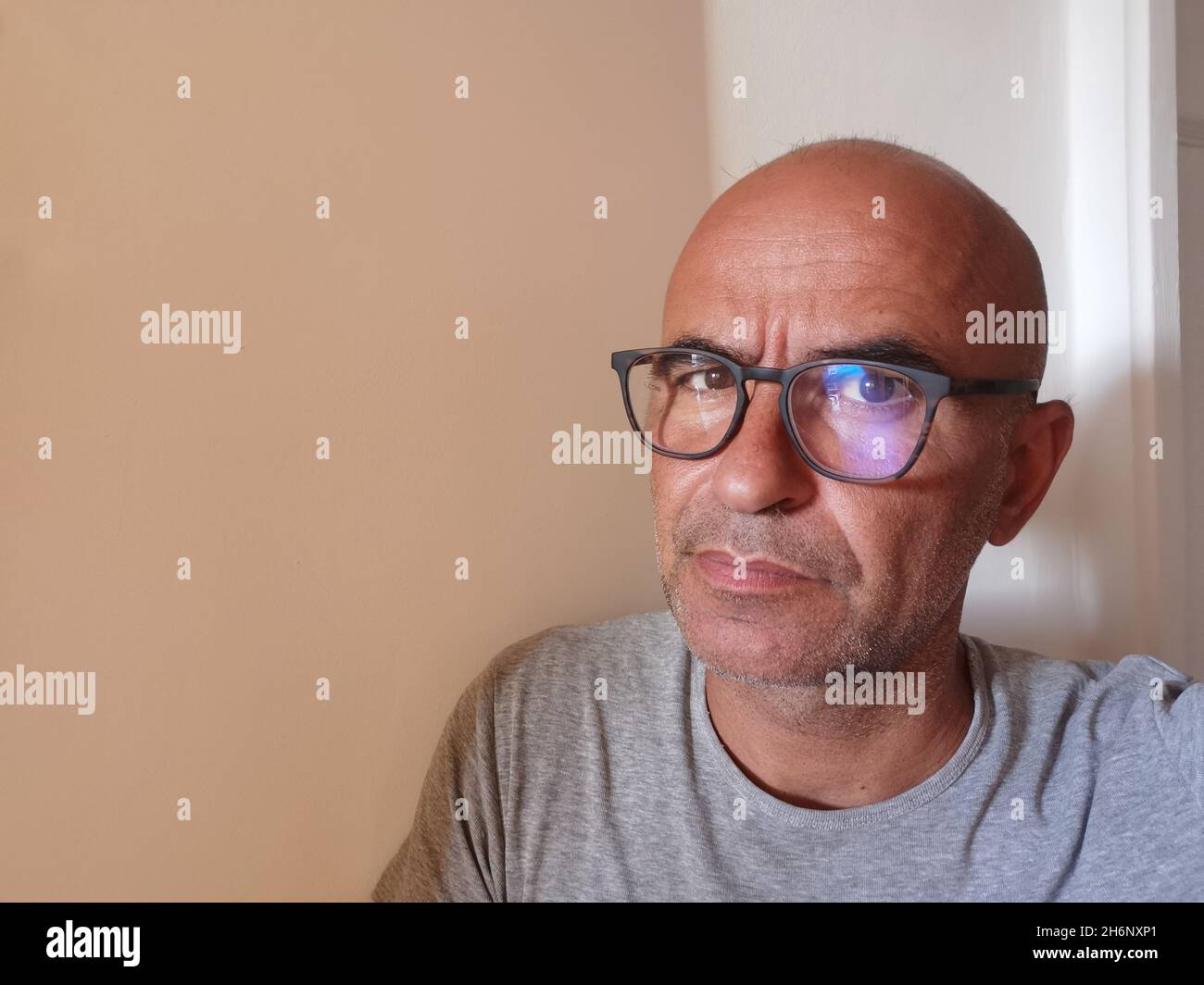 Portrait of a Hispanic bald male with sunglasses and a cautious facial ...