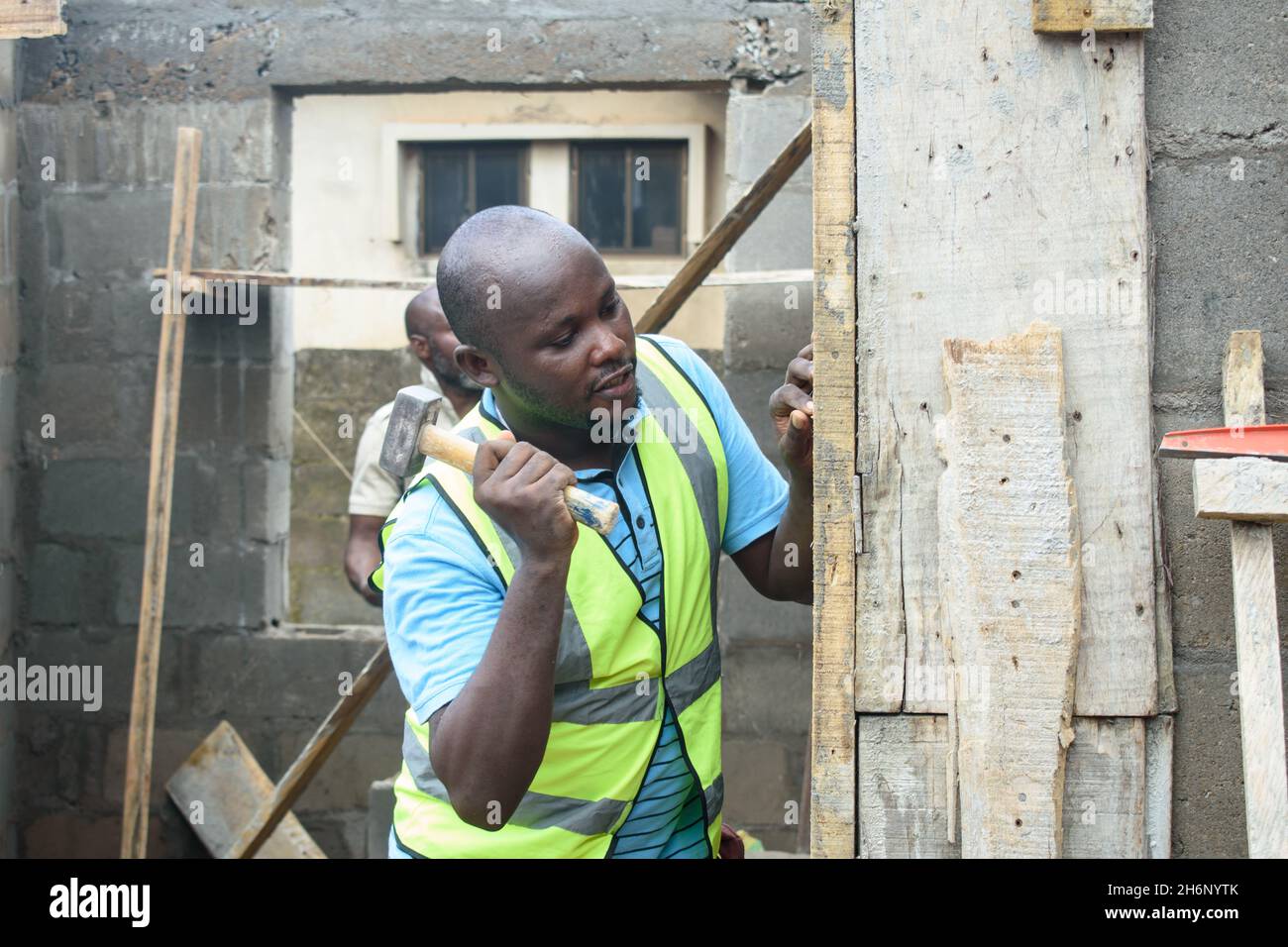African male construction worker working with a hammer on a building ...