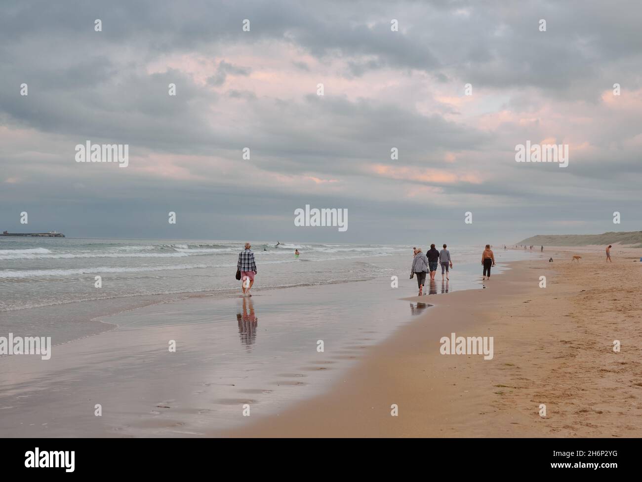 Walking along a summer beach on the Northumberland coast in Bamburgh ...
